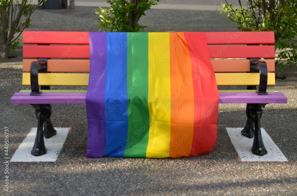 A bench painted in rainbow pride flag colors near Sheridan collage ...