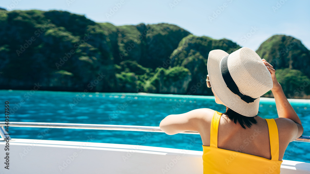 Rear view of adult traveller woman sit and relax on the sailing boat ...