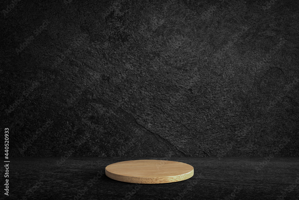 Round wooden product stand on black wall texture rough background dark ...