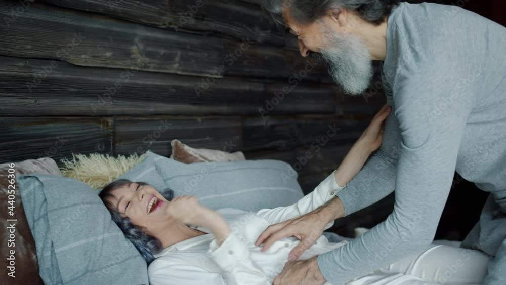 Slow motion of mature man tickling young woman in bed having fun ...