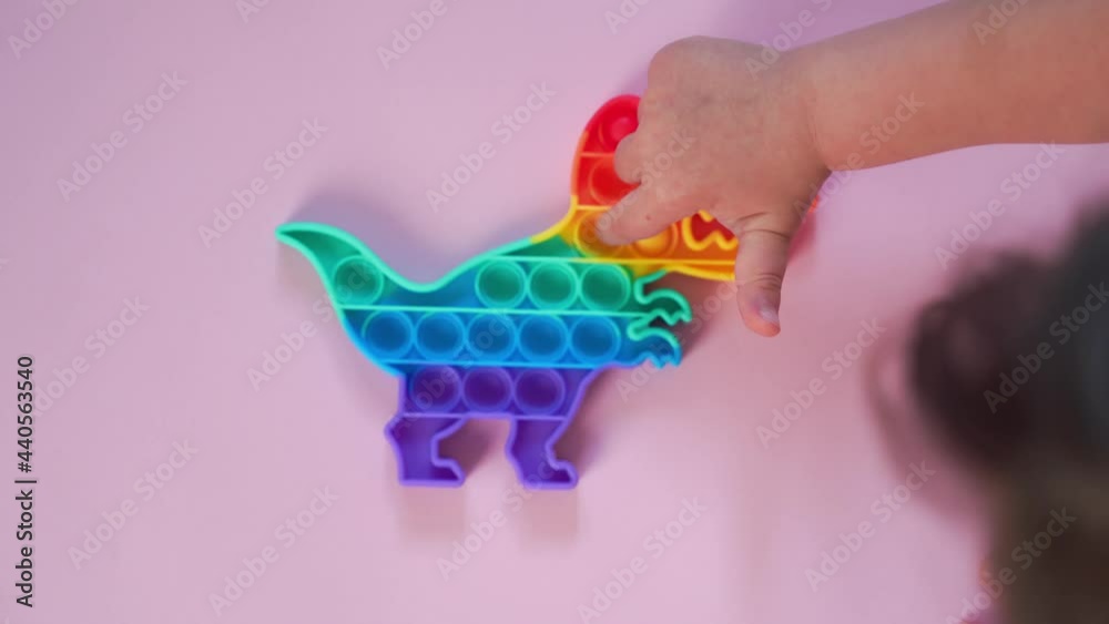 Popit rainbow toy in rainbow colours and dino shape. Trendy bubble pop ...