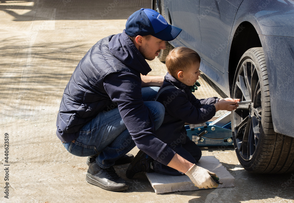 Father and son are fixing the car. The son helps the dad. Happy Father ...