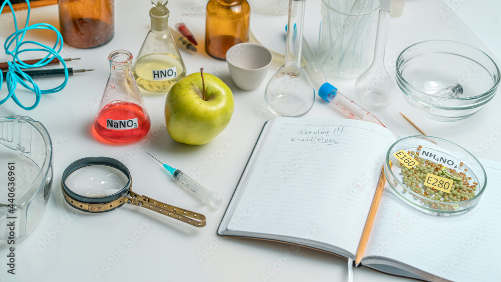 Food safety laboratory. View of a fresh ripe apple with test tubes and ...