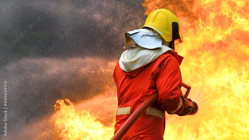 Professional Fireman in fire protection suit fighting strong fire in ...