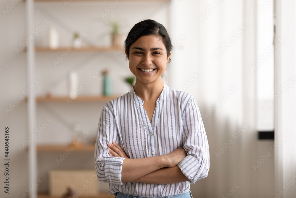 Portrait of happy young Indian female renter tenant stand arms crossed ...