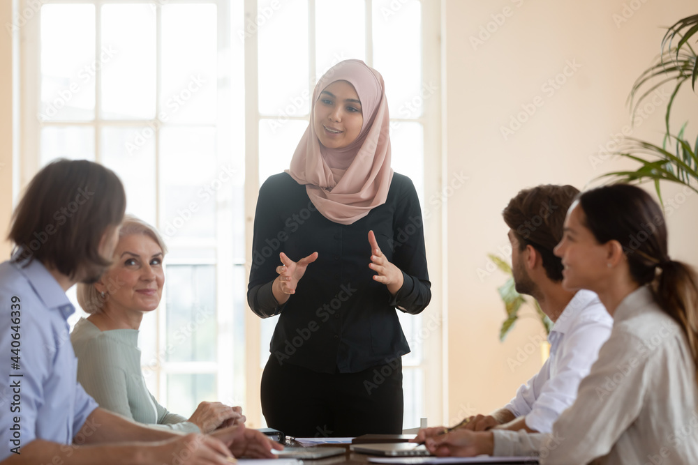 Foto de Smiling Asian muslim team leader talking to diverse employees ...
