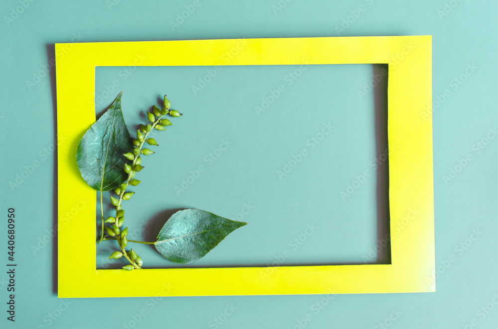 Yellow paper frame decorated with green leaves and branches on a ...