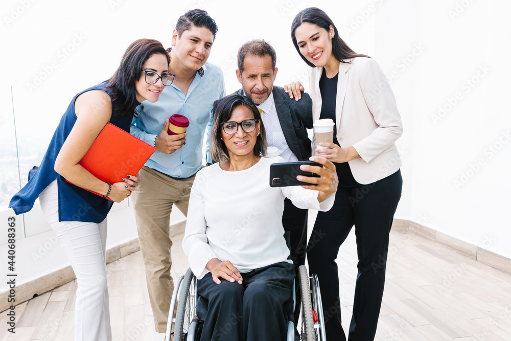 Latin transgender businesswoman in wheelchair with office workers ...
