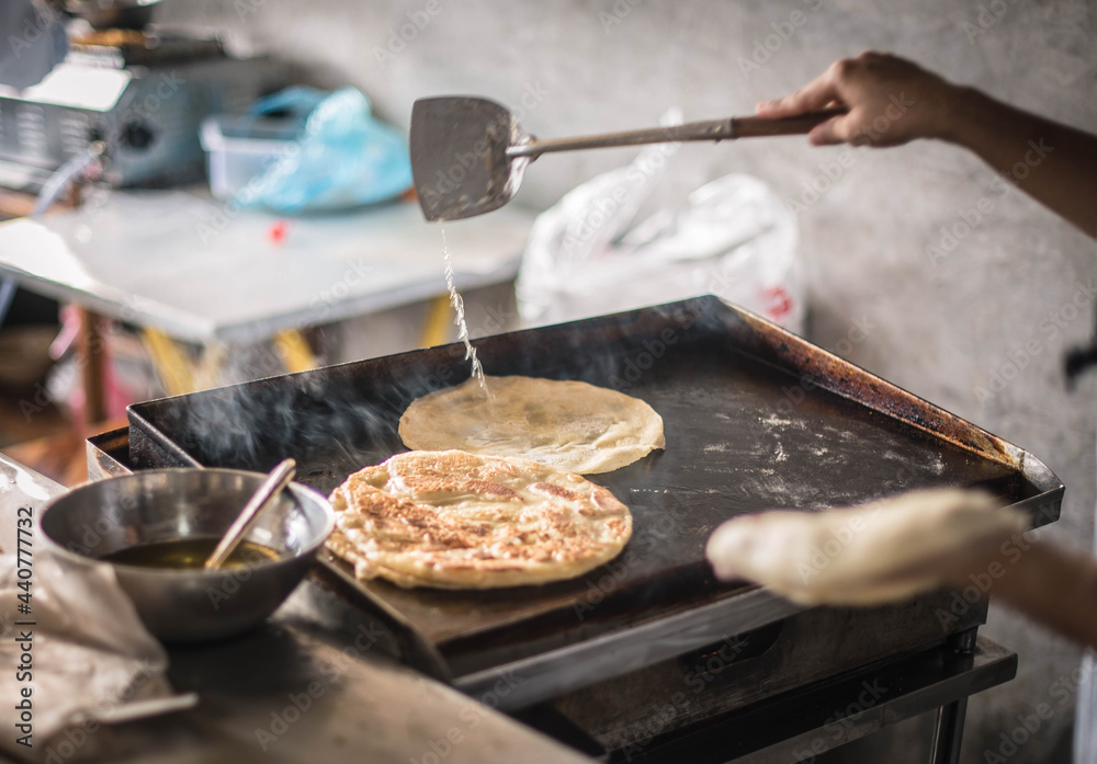 Flour is fried for making roti in a breakfast restaurant in Narathiwat ...