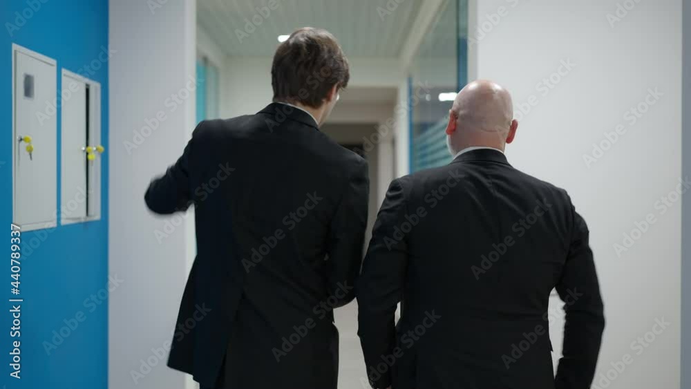 Live camera follows two confident elegant men walking in office ...