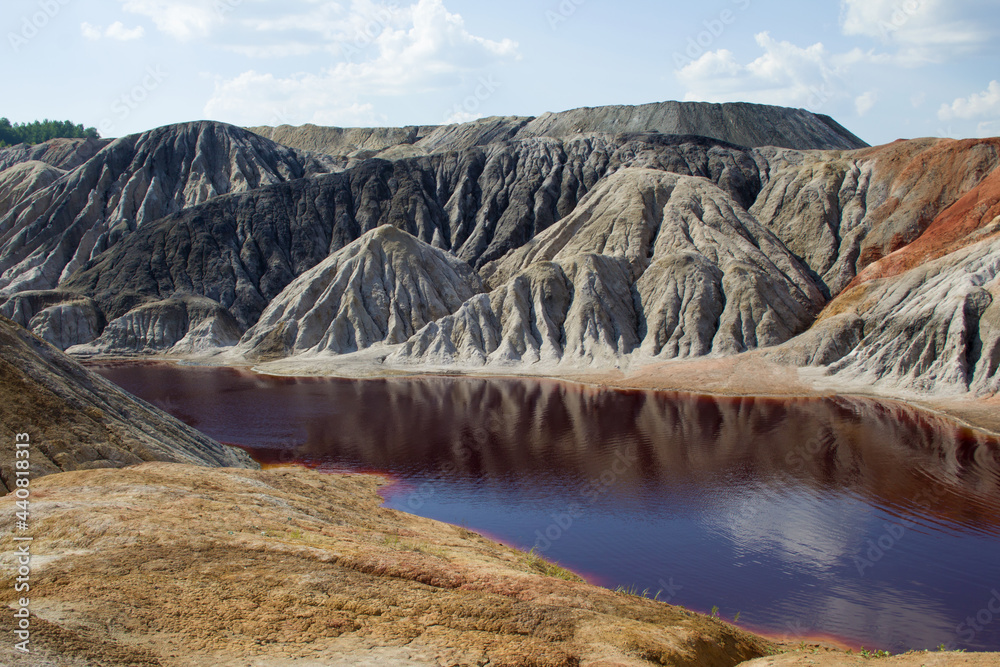 A dark red, acidic river against the backdrop of clay hills, a blue sky ...