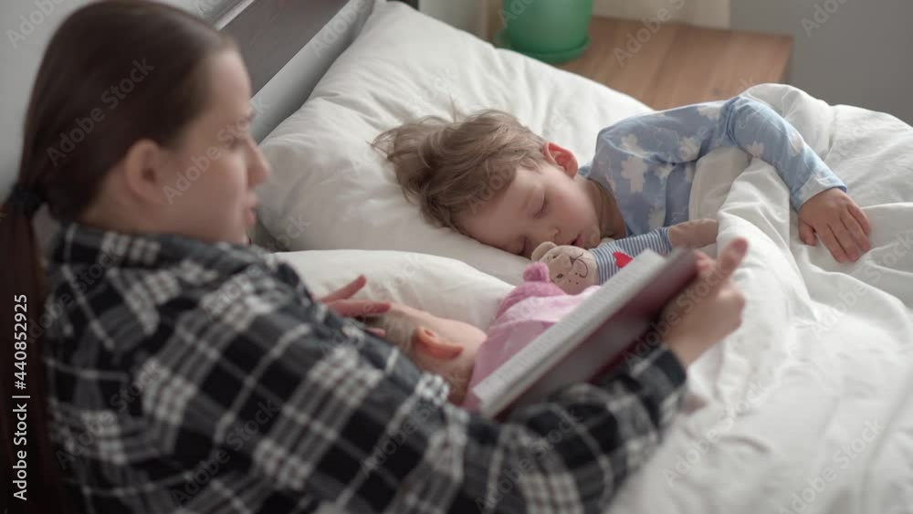 Authentic cute young woman or babysitter reads fairy tale from book to ...