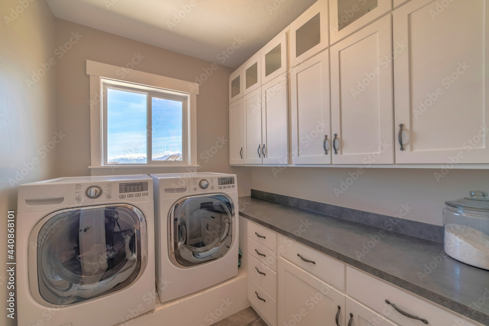 Laundry room with a washing machine, a dryer, and wooden cabinets for ...
