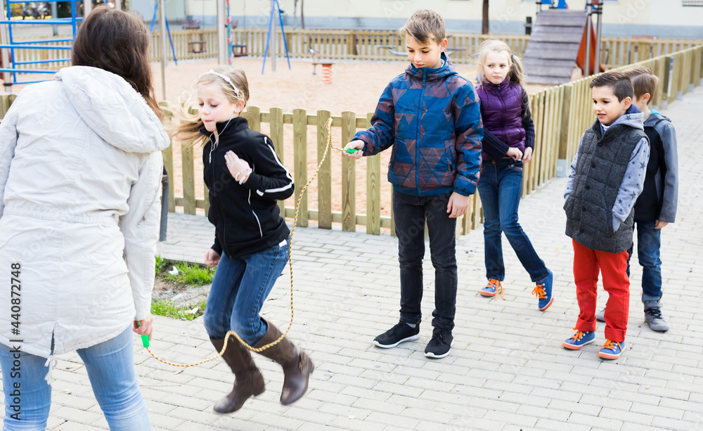 happy children playing rubber band jumping game and laughing outdoors ...