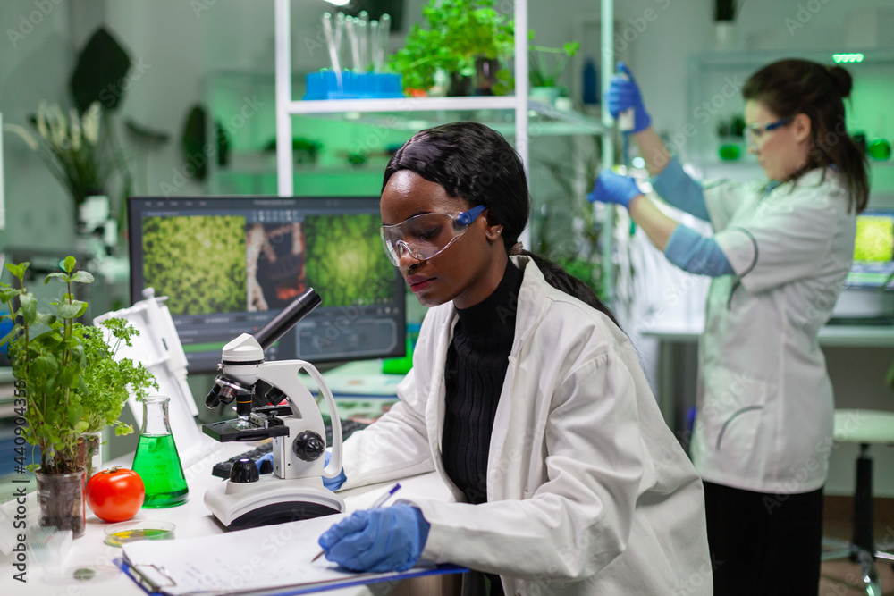 African biochemistry doctor examining chemical test using microscope ...