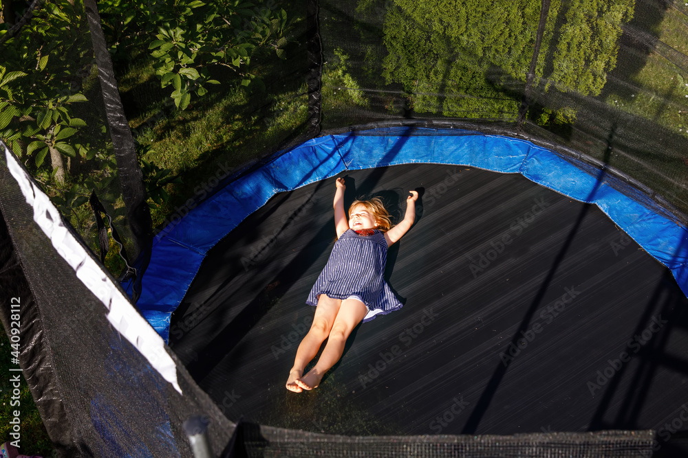 Little preschool girl jumping on trampoline. Happy funny toddler child ...
