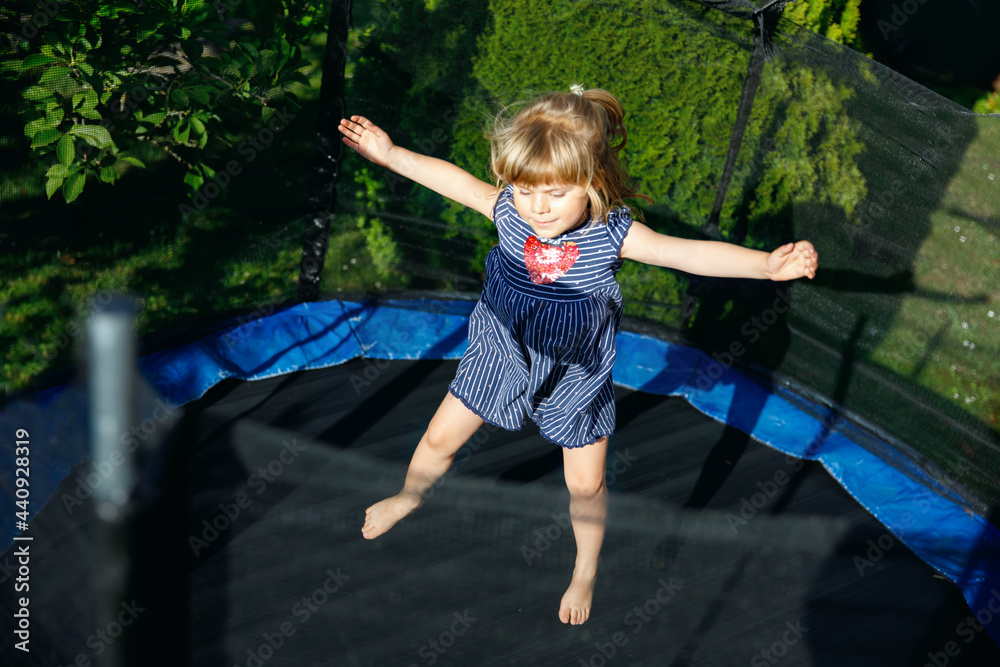 Little preschool girl jumping on trampoline. Happy funny toddler child ...