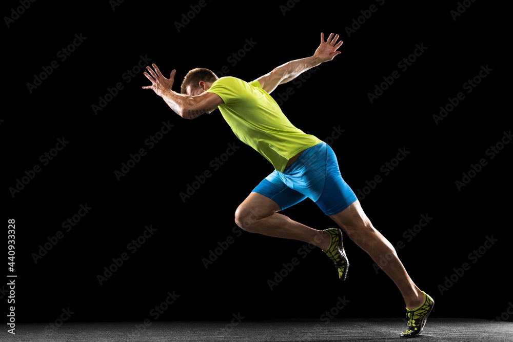 Caucasian professional male athlete, runner training isolated on black ...