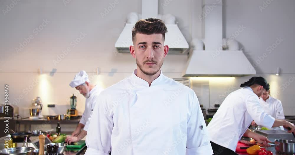 Close up portrait of young handsome sad male chef standing at kitchen ...