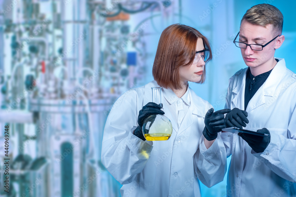 Young scientists at background of bioreactor. Two biologists are doing ...