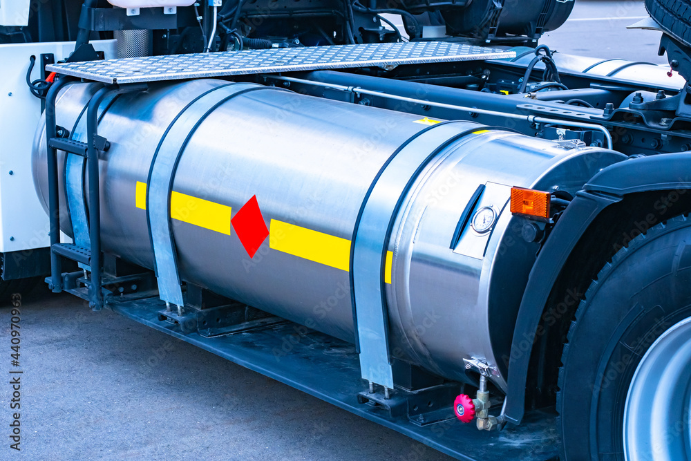 LPG tank on a truck. A silver LPG tank next to wheels of a large truck ...