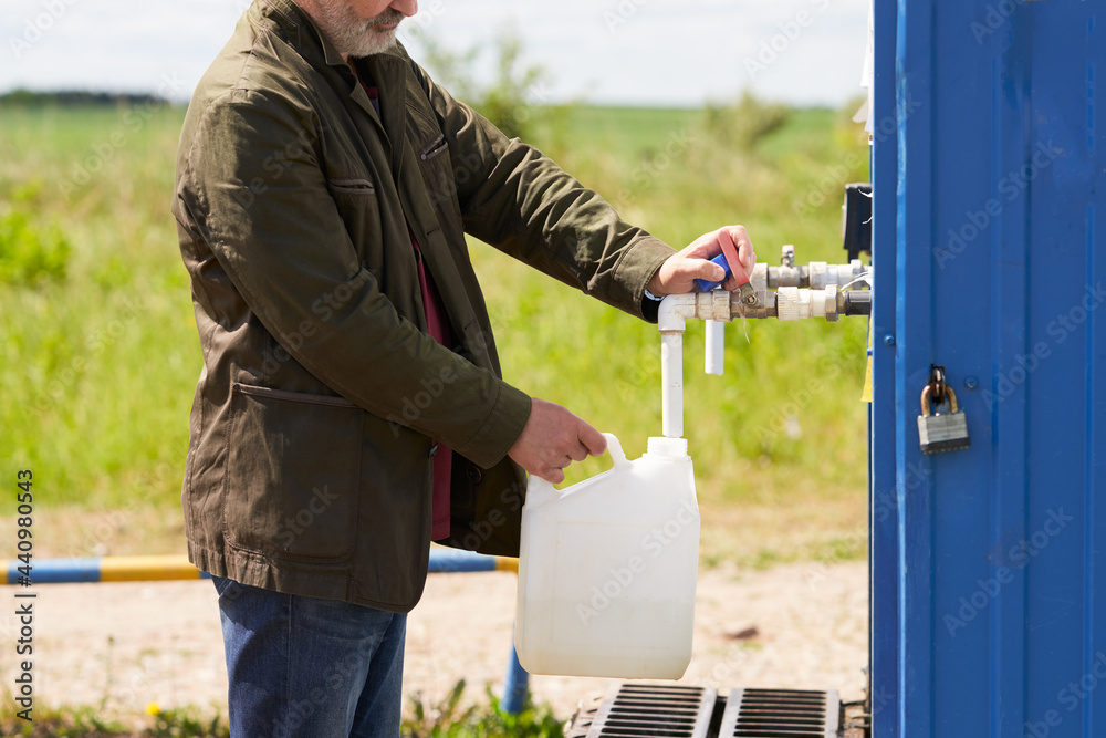 A man draws water from the water intake well's flow tank into a plastic ...