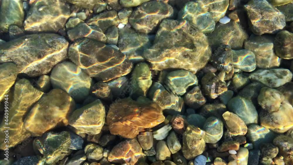 Top view of beautiful multi-colored stones at the bottom of a river or ...