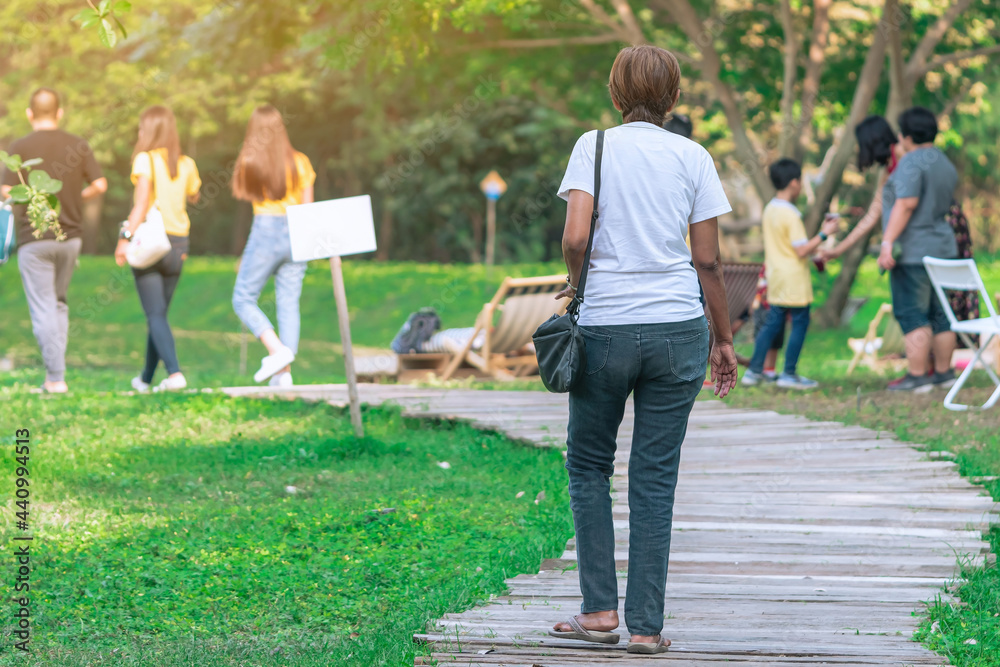 Back view of Asian woman walk alone on pathway through green garden ...