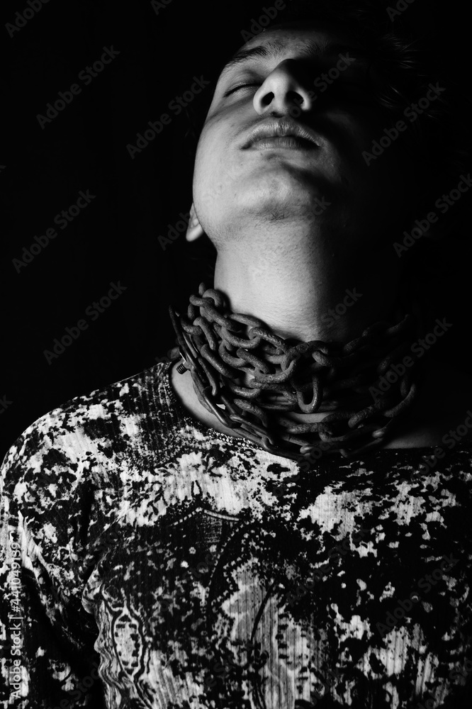 Vertical portrait of a young asian man with a metal chain around his ...