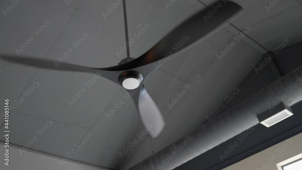 This video shows a modern industrial style fan rotating in the ceiling ...