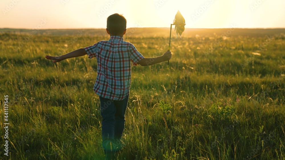 Happy kid plays with toy pinwheel outdoors in spring park in sunshine ...