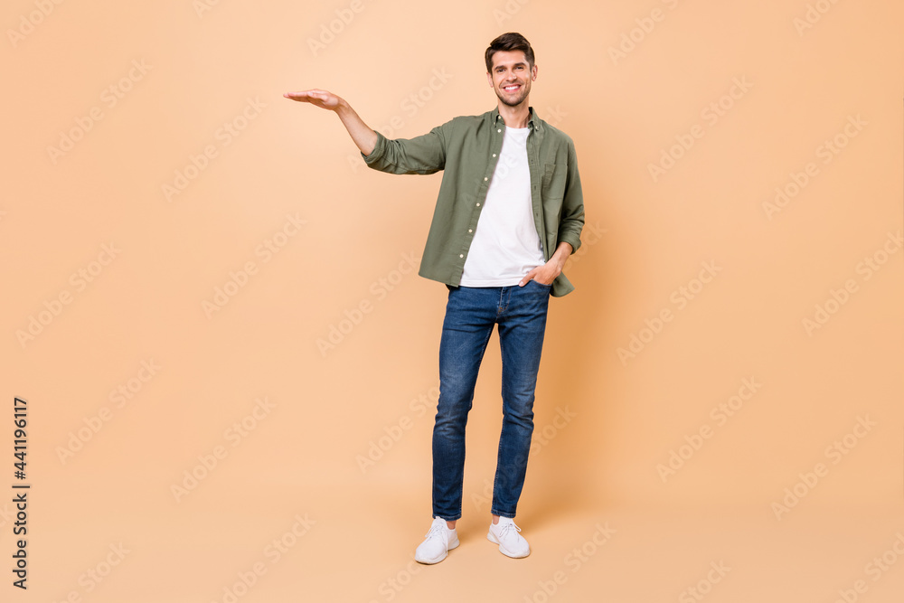 Full body photo of attractive young happy man hold hand empty space ...