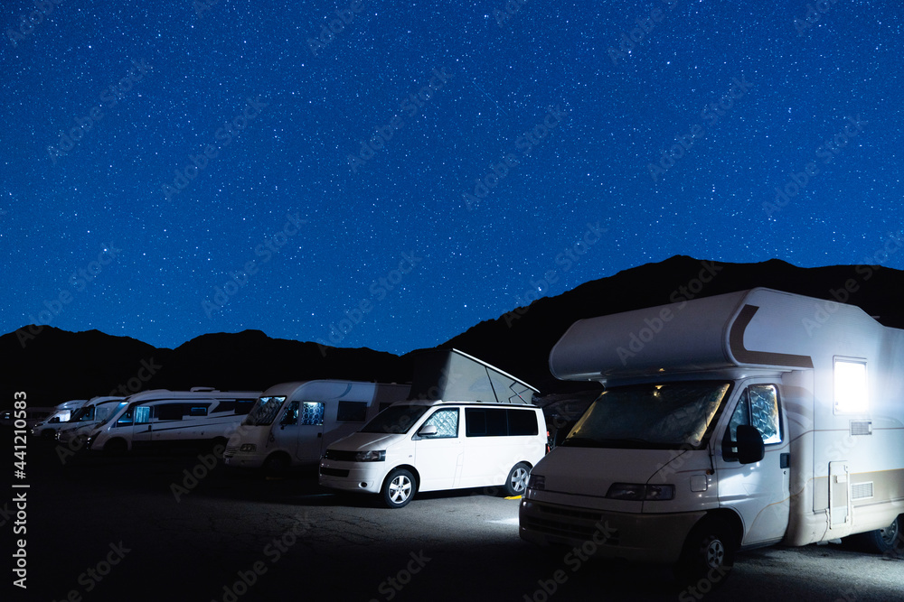 Campers parked in a caravan parking area sleeping on a starry night in ...