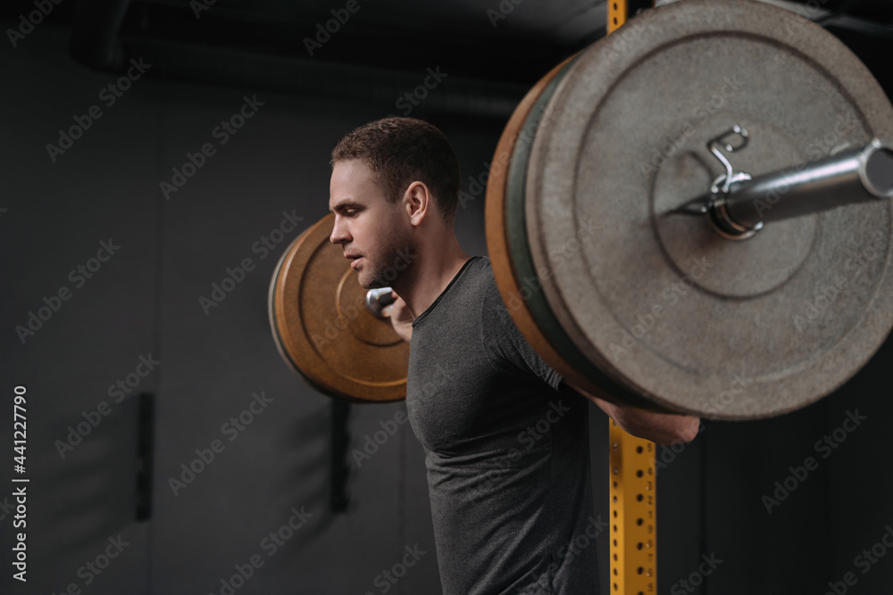 Portrait of male bodybuilder doing back squats in gym. Muscular ...