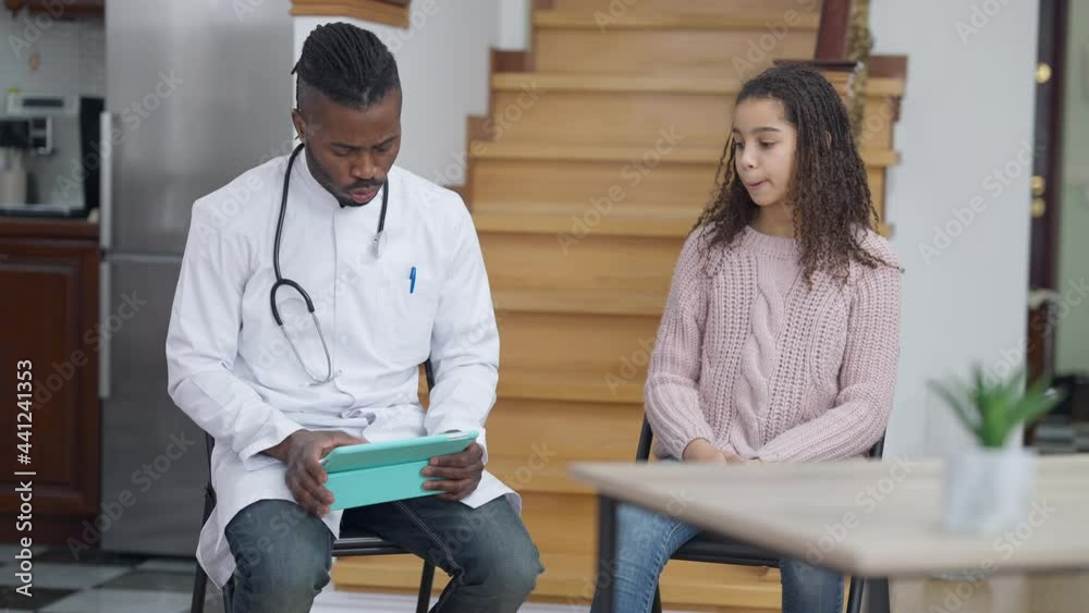 Family doctor visiting teenage African American girl at home checking ...