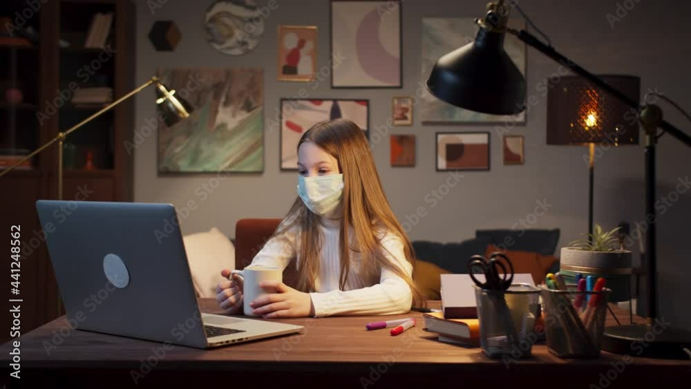 Pretty small girl pupil in mask using laptop computer for remote ...