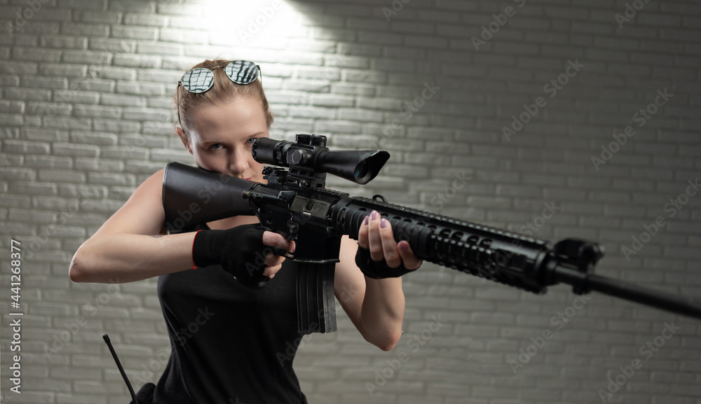 a young female soldier poses with an automatic rifle with a telescopic ...