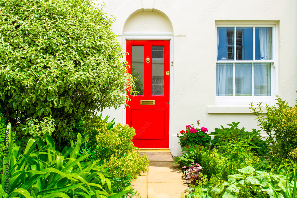 Typical British front of the house with the garden. Red door in white ...