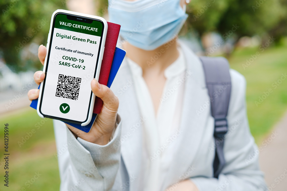 Unrecognized woman in mask with backpack holding smartphone with ...