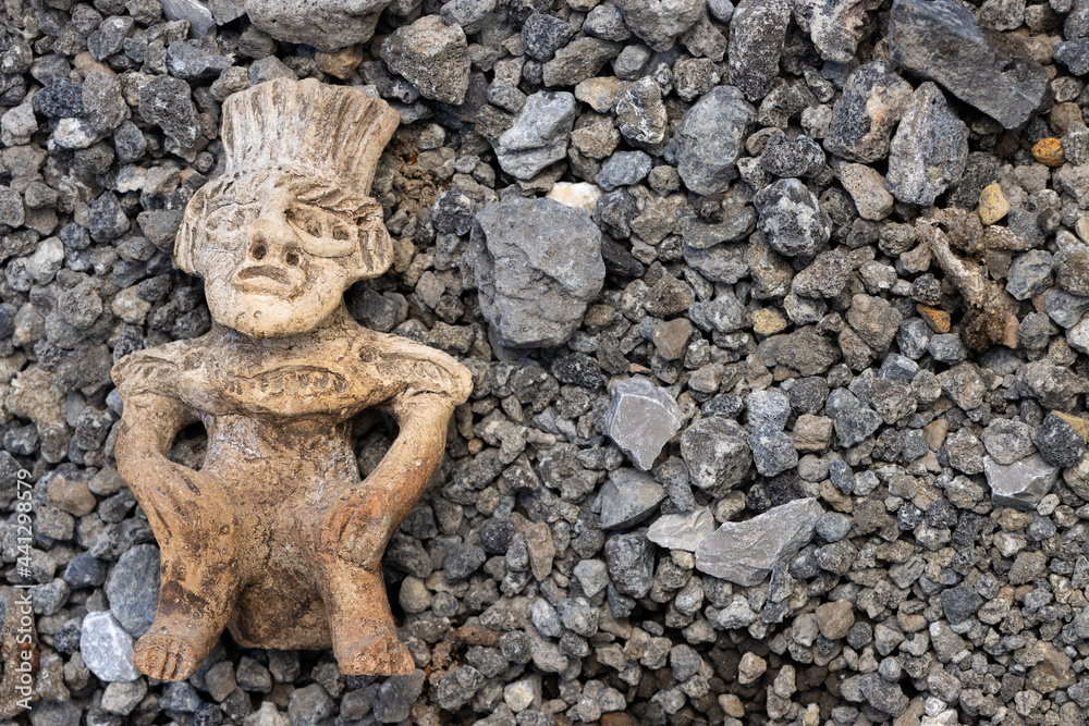 Statue of an Aztec warrior made of clay in front of a background of ...