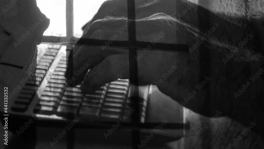 Prison bars are placed on the hands of a programmer typing a code on a ...