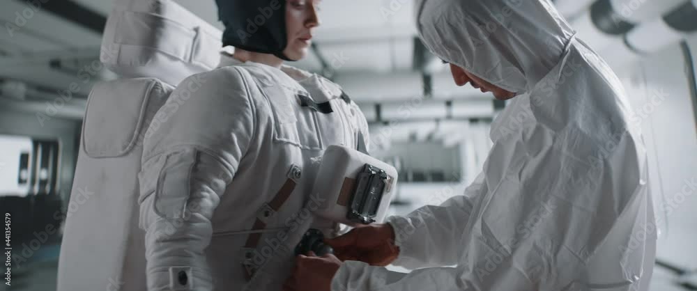 Crew member performing pre-flight inspection on a female astronaut ...
