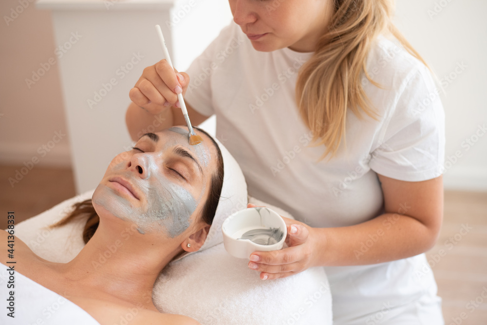 Cleaning and moisturise nourish skin of face. Cosmetologist put grey ...