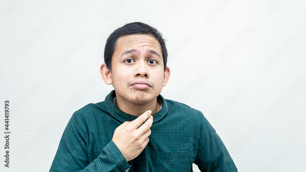 A portrait of young Asian Malay man holding chin checking his face for ...