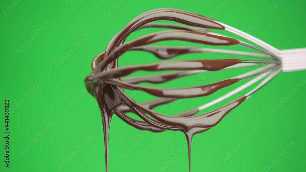 Melted chocolate dripping from a metal whisk on a green screen ...