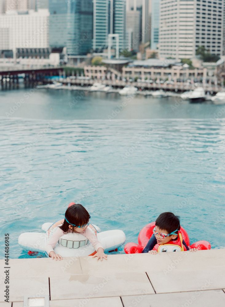 Two little kids swimming on infinity pool on holidays in Sydney CBD ...