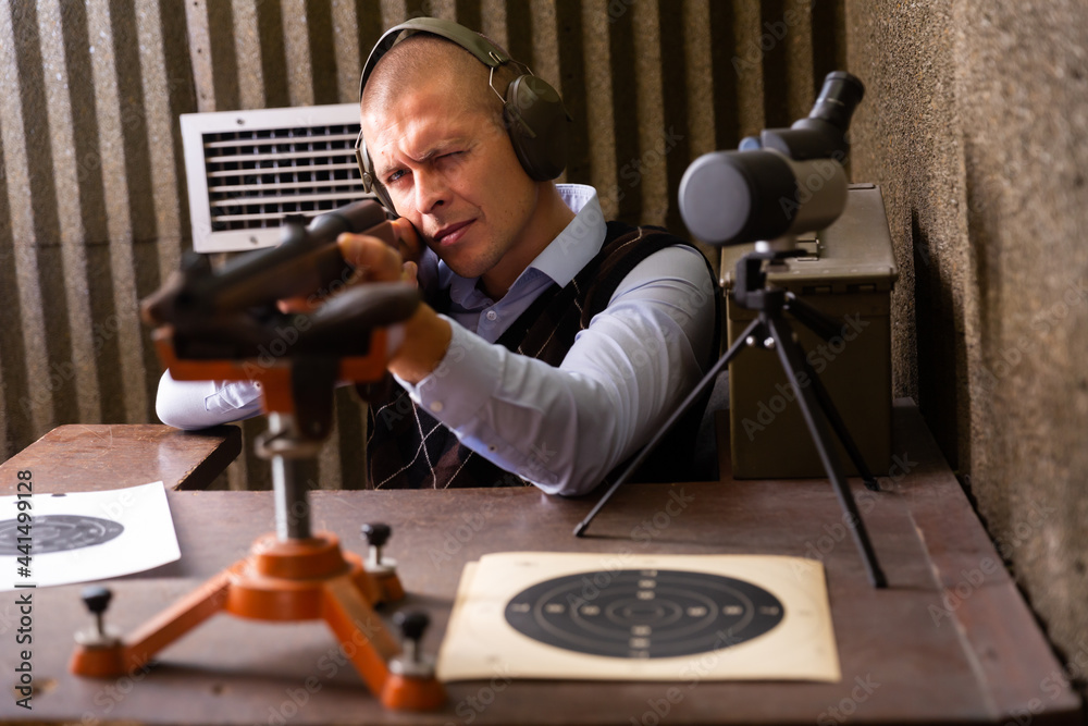 Man aims at a target with a semi-automatic rifle in a shooting range ...