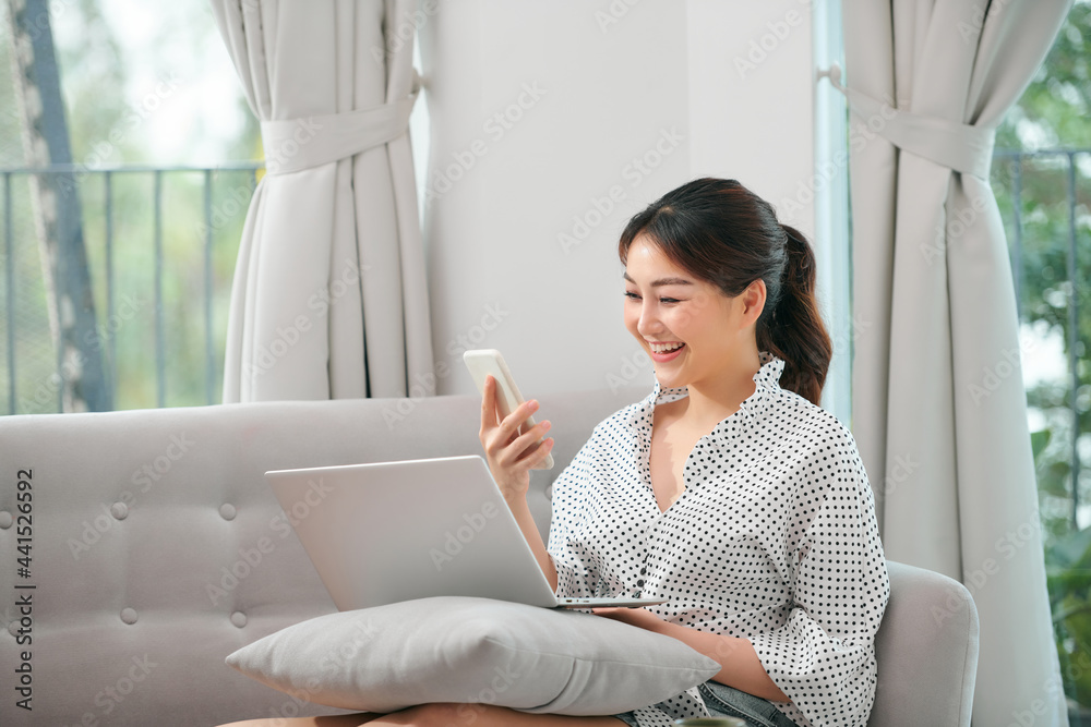 girl using laptop and smartphone. Young woman in casual clothes with ...