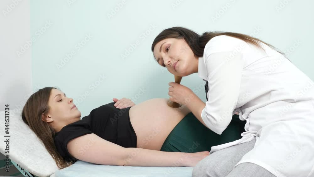 Careful female gynecologist puts fetoscope on pregnant woman belly to ...