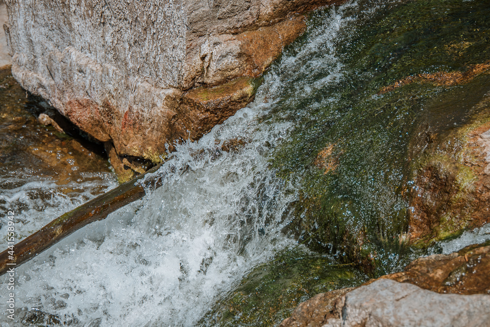 Selective focus close-up of clear stream water running over large rocks ...